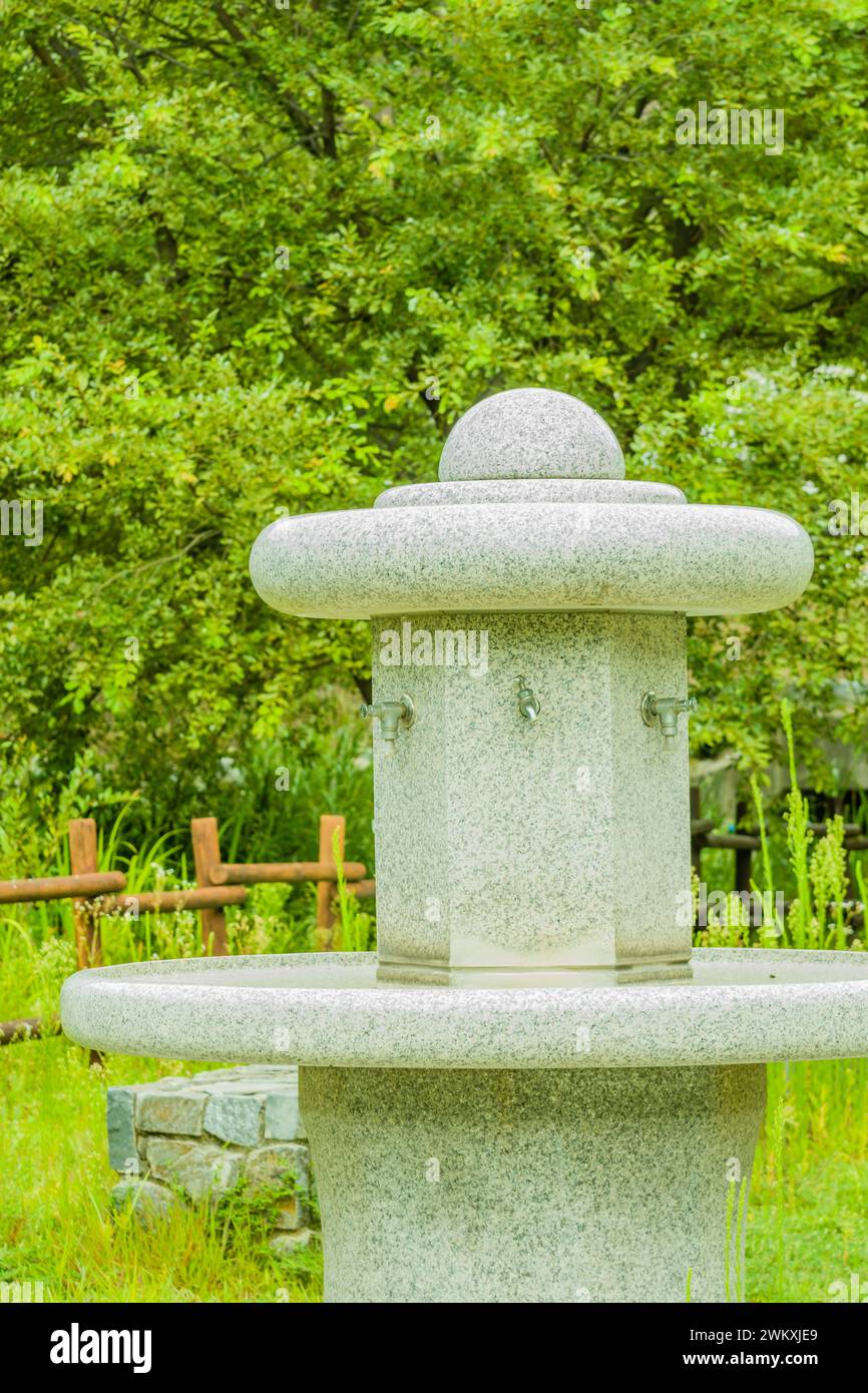 Large hand washing water fountain in a public park with lush green ...
