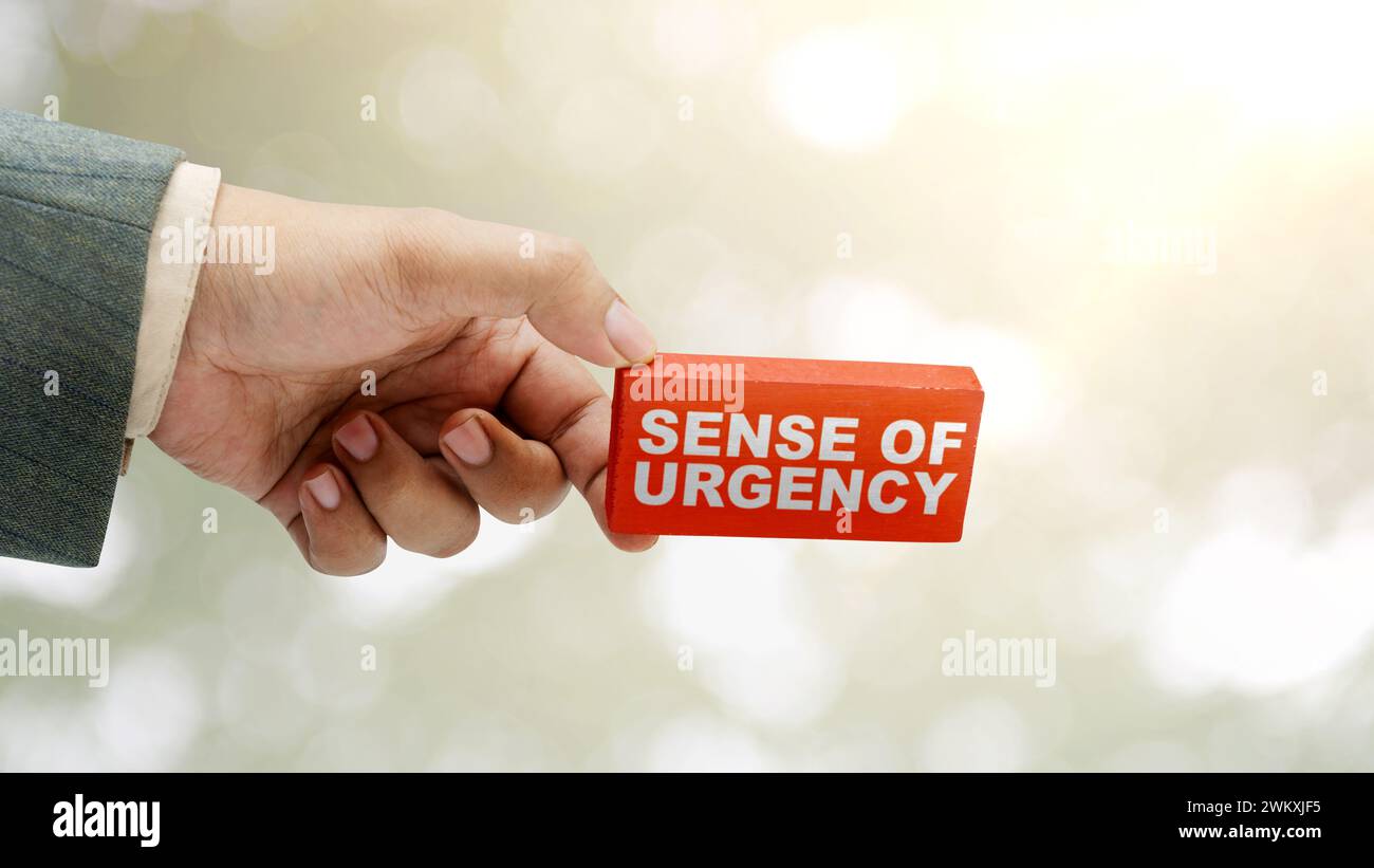 Business hand holding a wooden block with 'sense of urgency' text ...