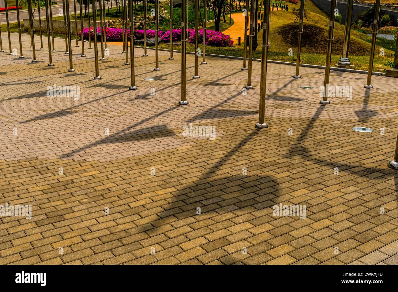 Shadows of flags on brick walkway between rows of chrome flagpoles in ...