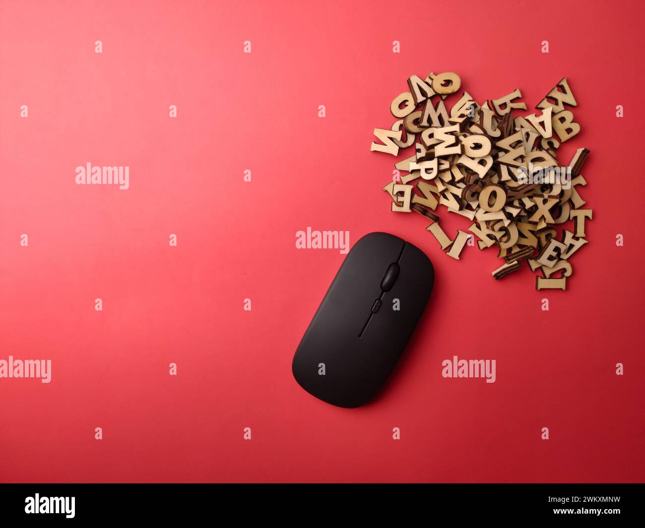 Top view black mouse and wooden words on a red background with copy and ...