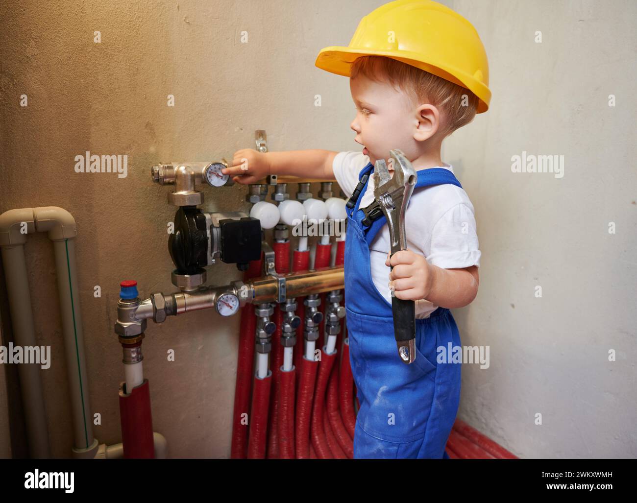 Child in safety construction helmet holding wrench tool and pointing at ...
