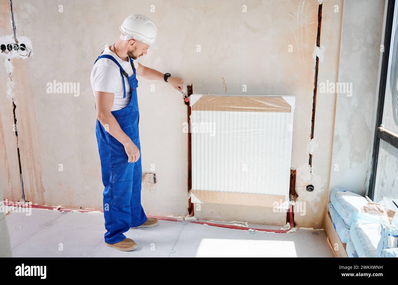Male plumber in work overalls using wrench tool while installing ...