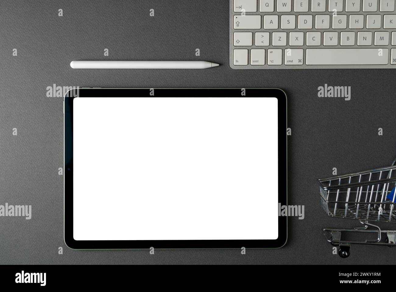 Tablet with blank screen, keyboard and supermarket cart on dark gray ...