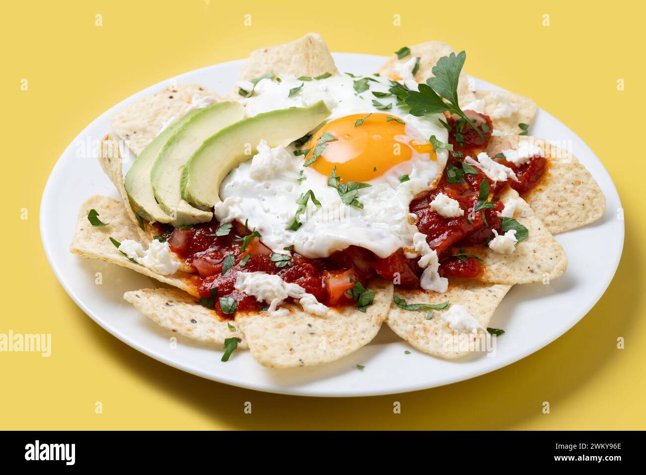 Traditional Mexican breakfast red chilaquiles with egg on yellow ...