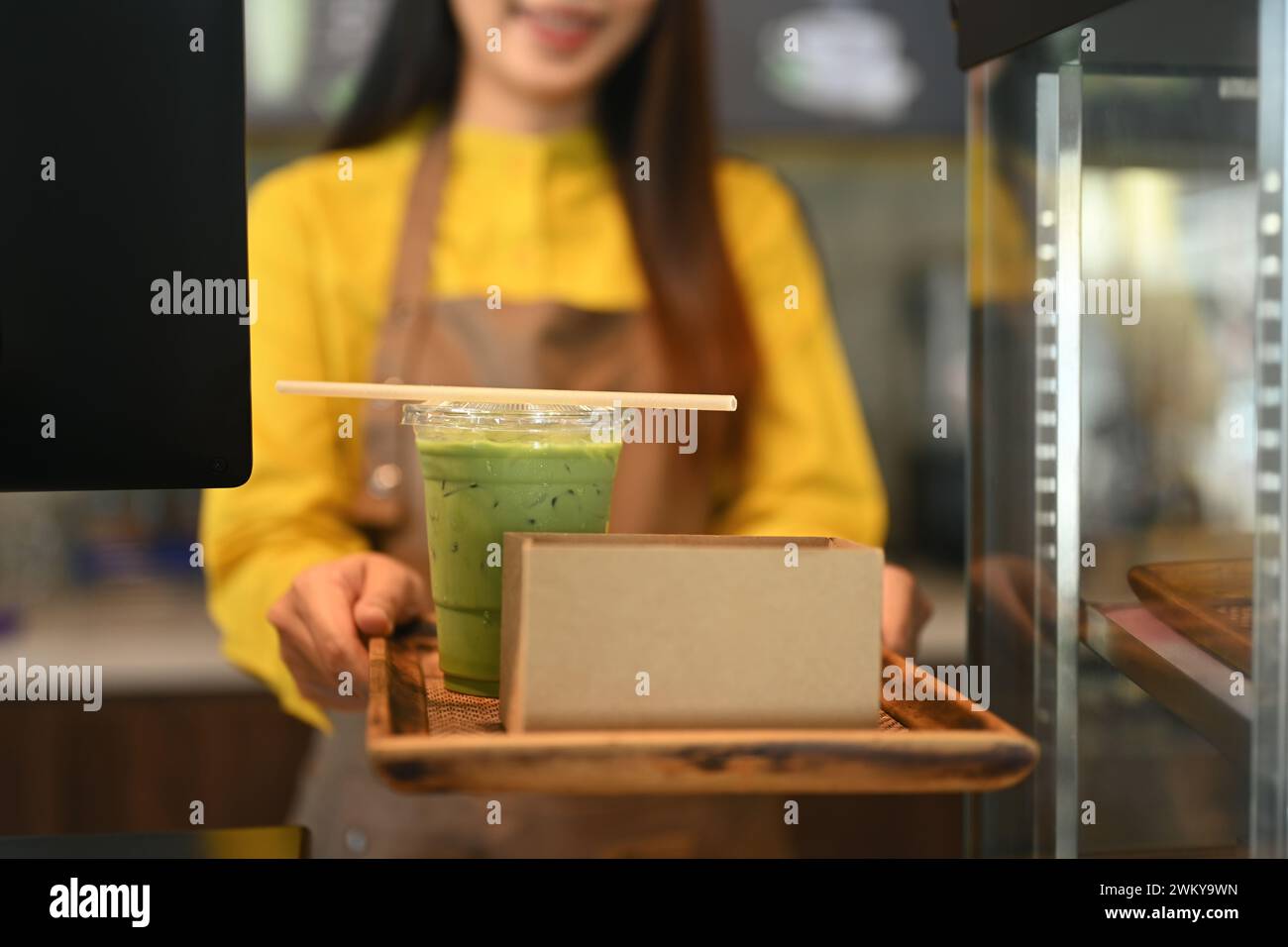 Female waiter in apron serving cold drink paper straw and cake in a ...