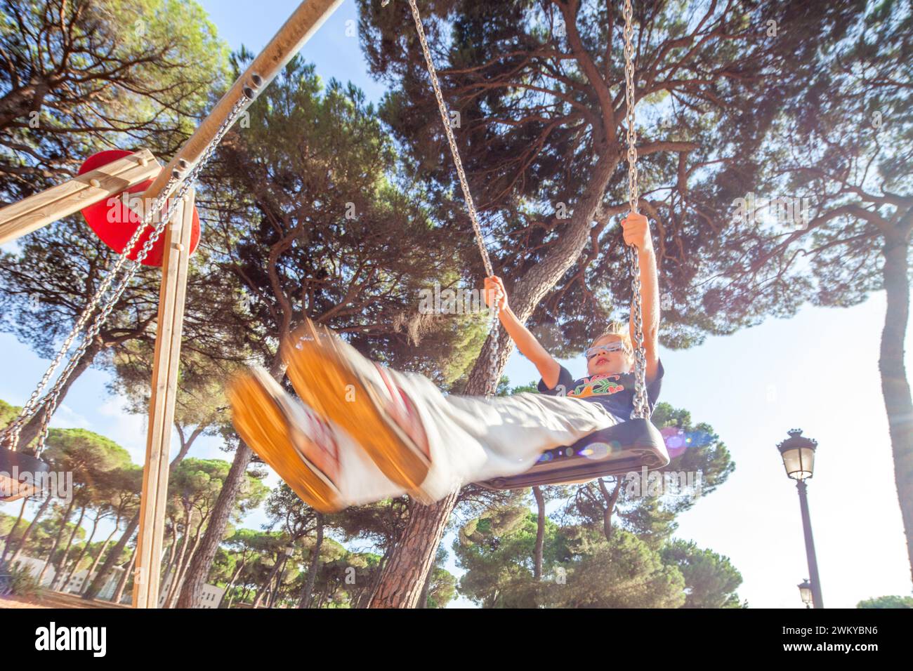 A child enjoys a swing set surrounded by pine trees in Hinojos, Spain ...