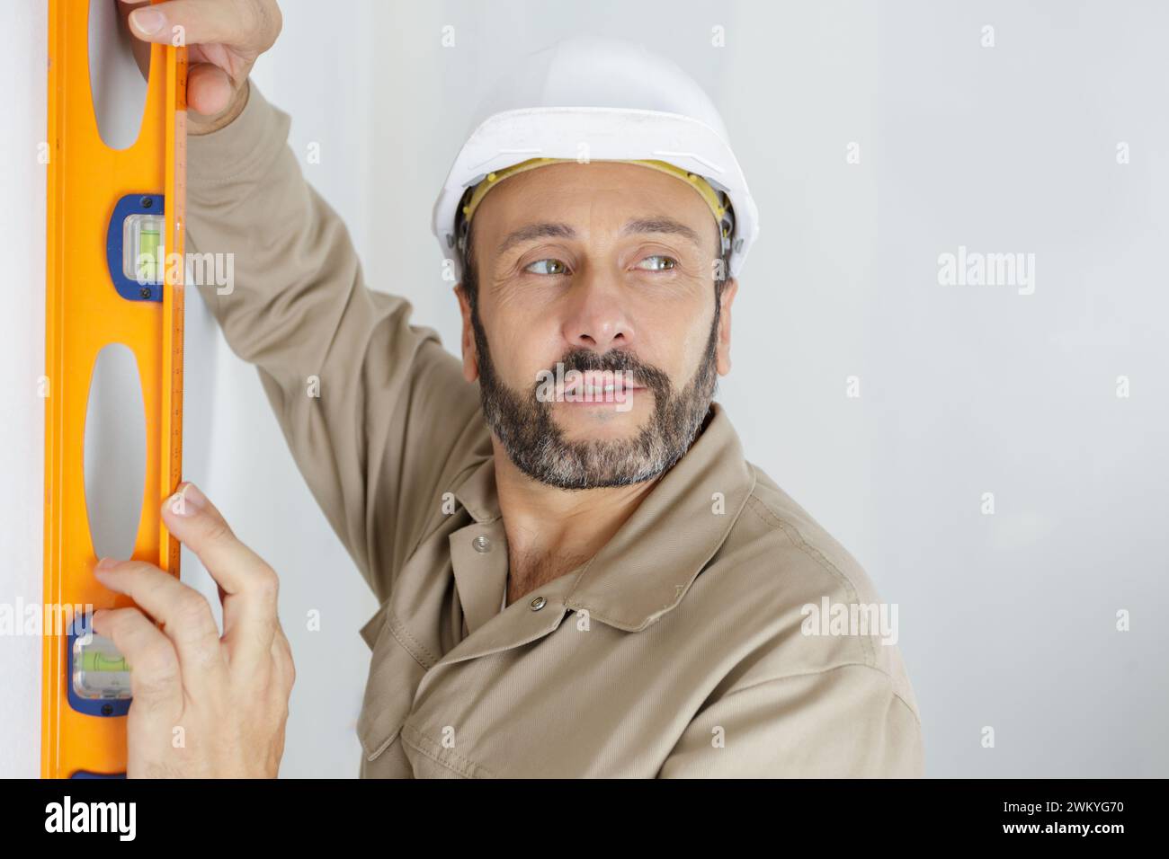 mature tradesman holding spirit level vertically Stock Photo - Alamy
