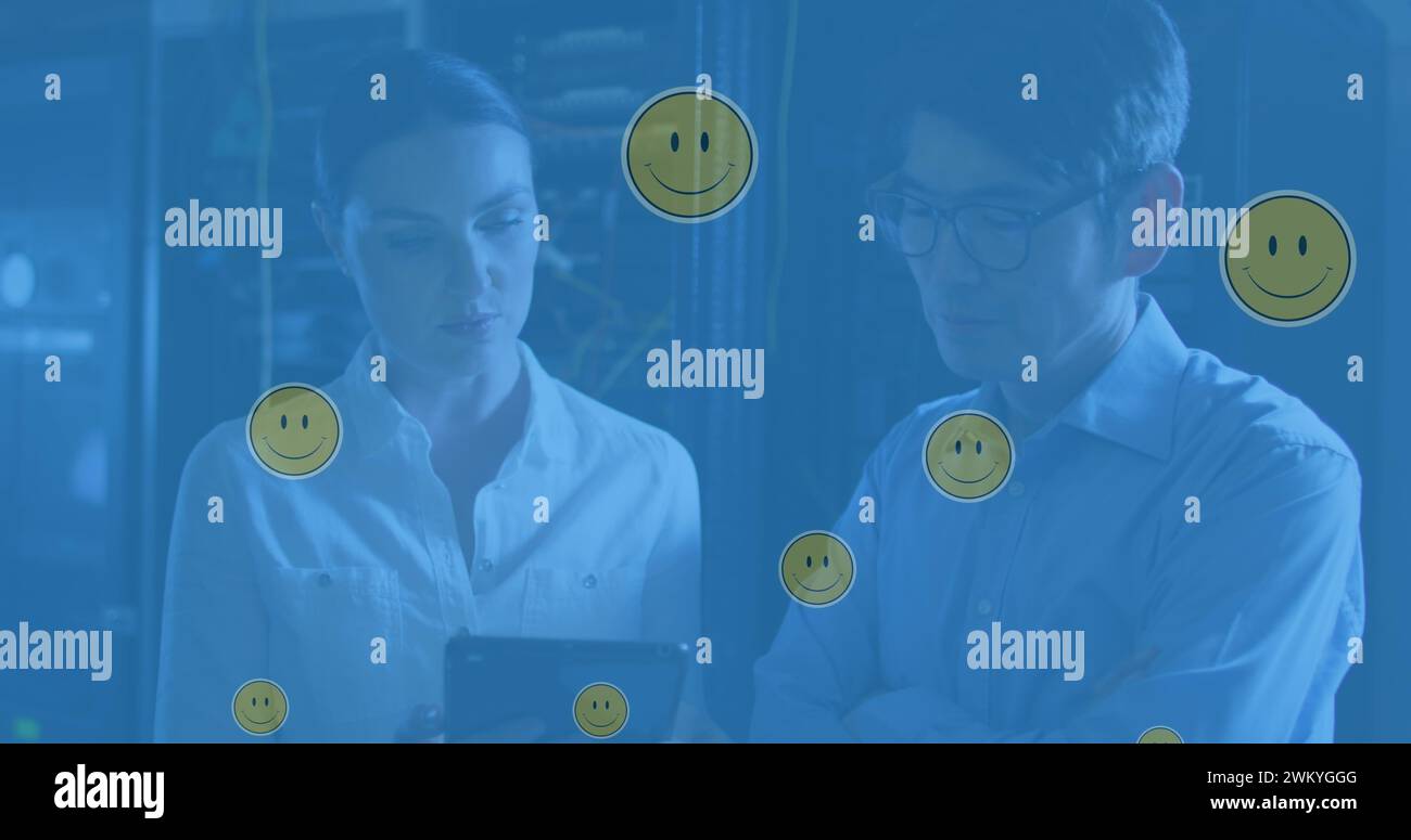 Image of falling emoji over diverse couple of server room workers Stock ...
