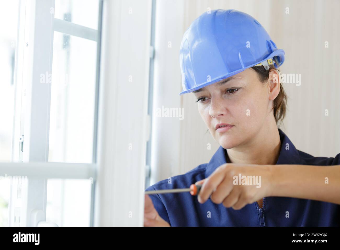 female window fitter using screwdriver to fit window Stock Photo - Alamy