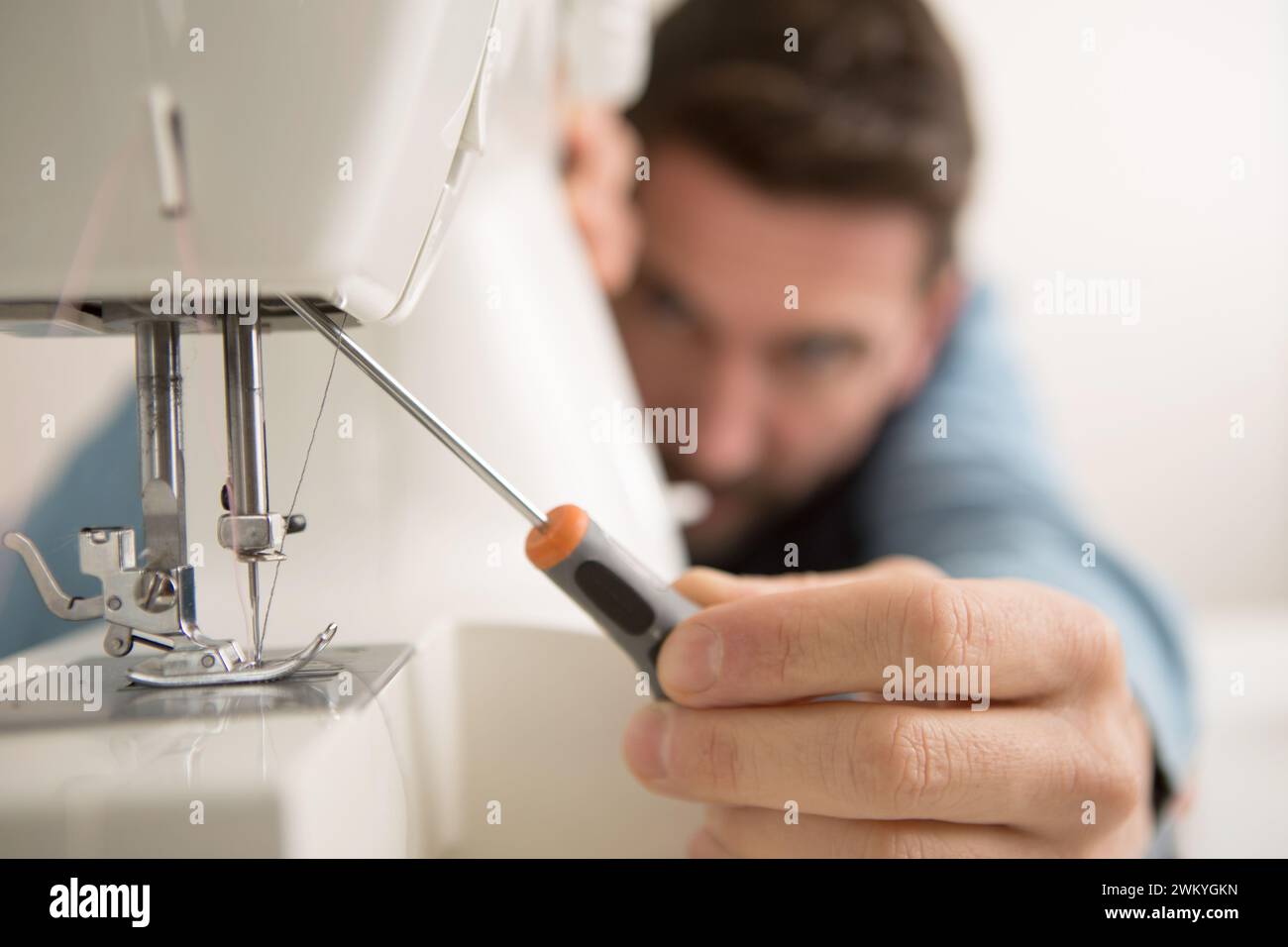 man repairing sewing machine with a screwdriver Stock Photo - Alamy