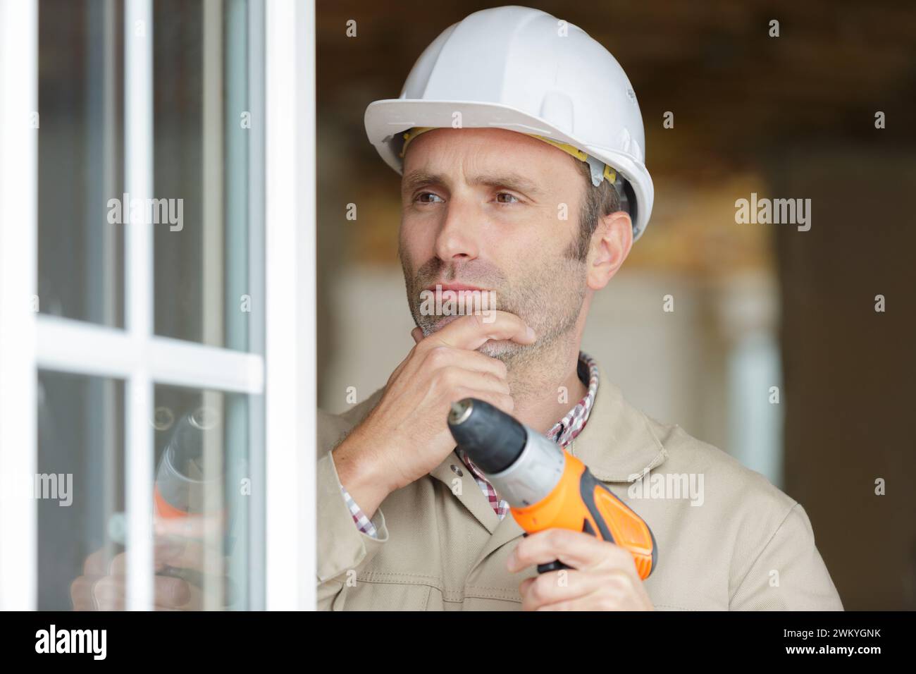 builder drills a hole in window Stock Photo - Alamy