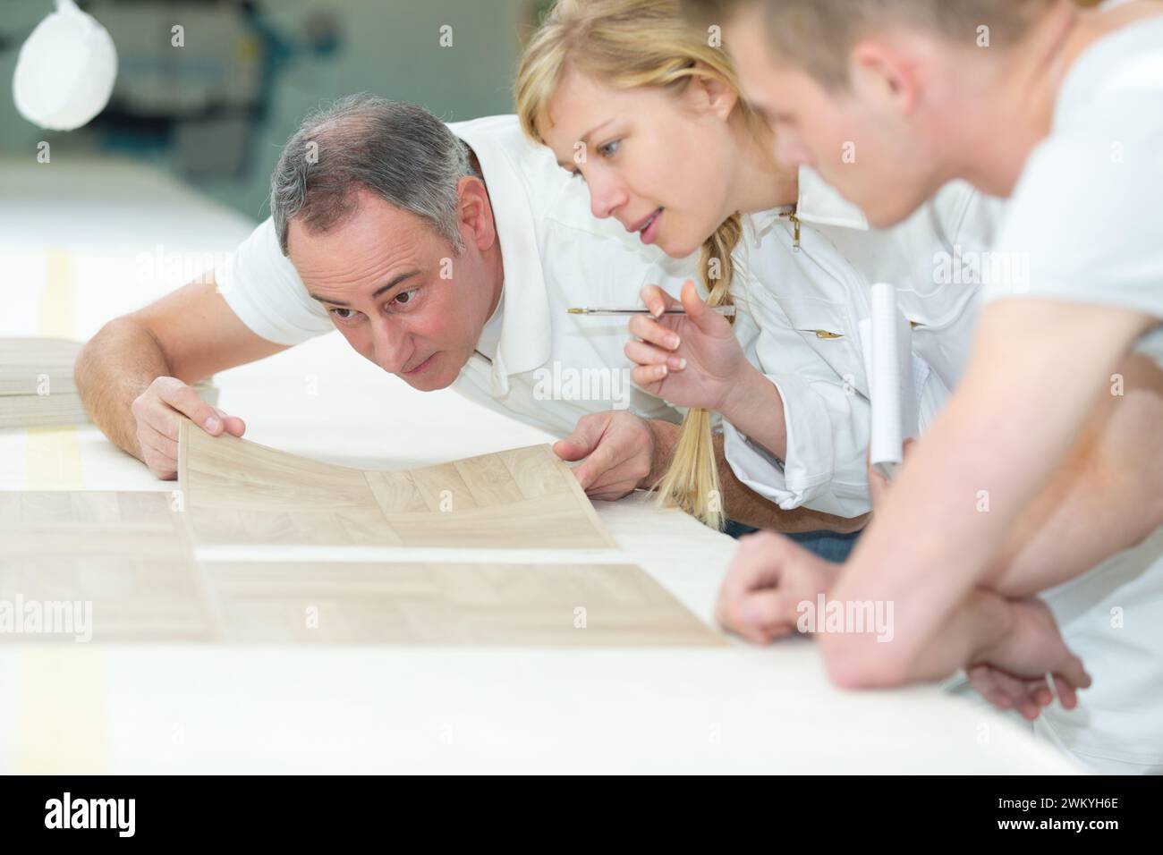 tiler showing apprentice how to place boards Stock Photo - Alamy