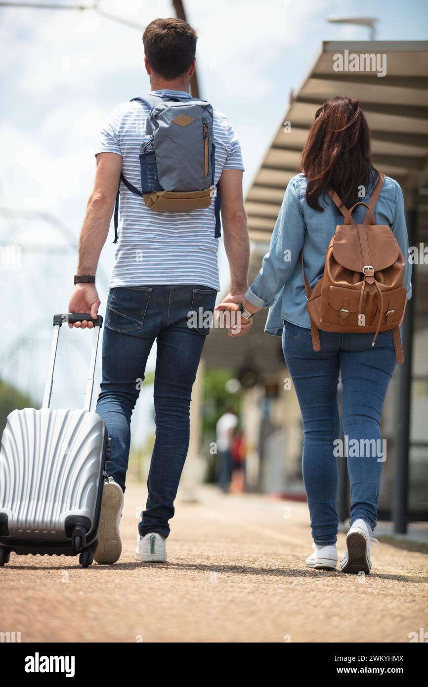 couple on train station pulling trolley luggage Stock Photo - Alamy