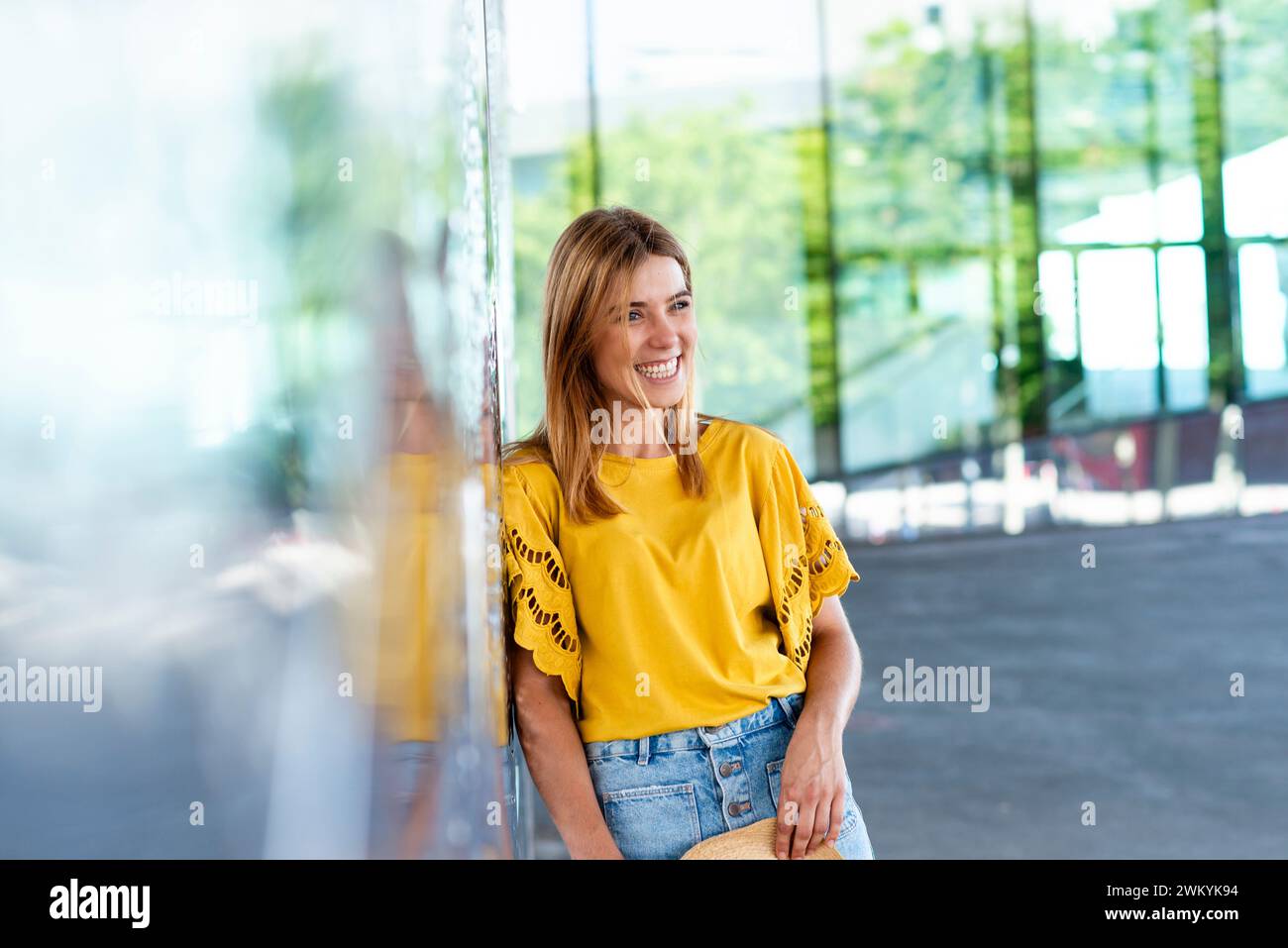 A candid moment captured of a young woman smiling, dressed in a summer ...