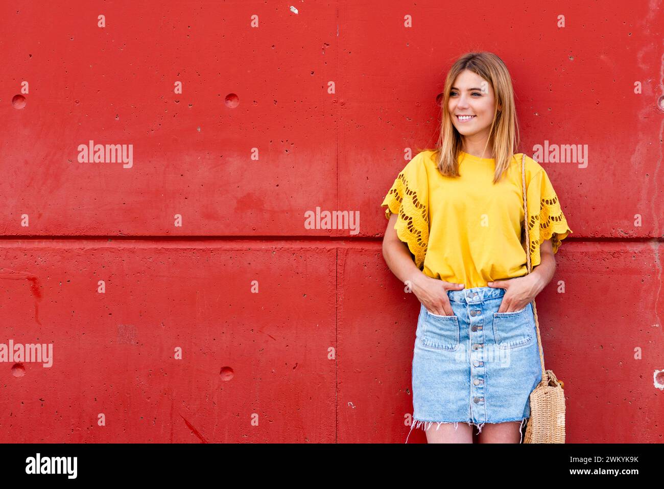 In this portrait, a young woman stands confidently against a rich red ...