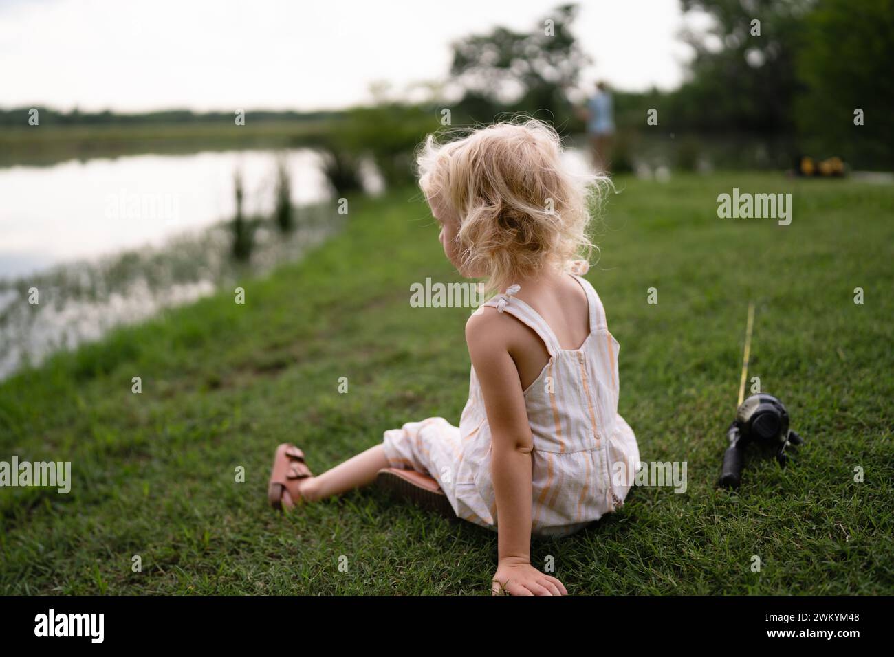 Little Girl Sitting Near Pond With Fishing Pole Stock Photo - Alamy