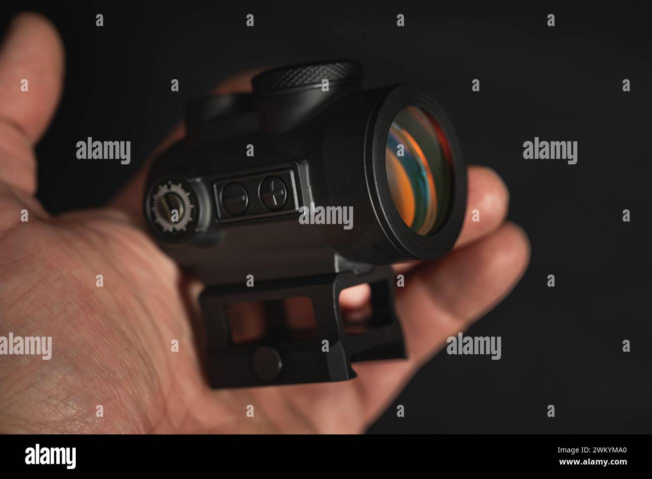 A modern red dot sight in a man’s hand, close-up photo. High quality ...