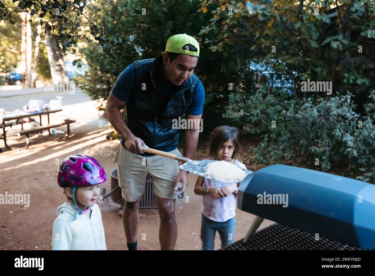 Father making homemade pizza with daughters while camping Stock Photo ...