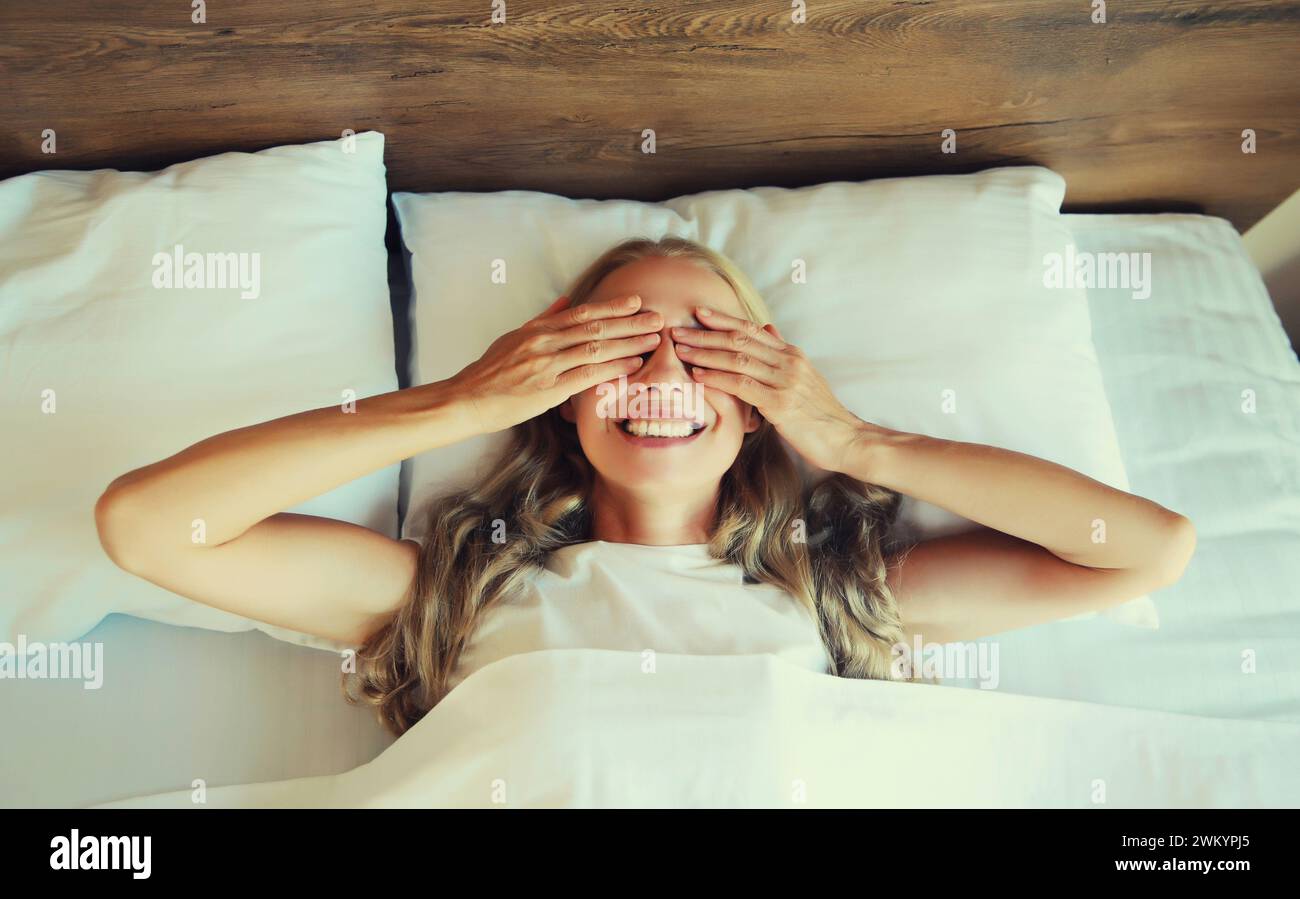 Healthy sleep, relaxed middle aged woman wakes up lying on the bed in ...