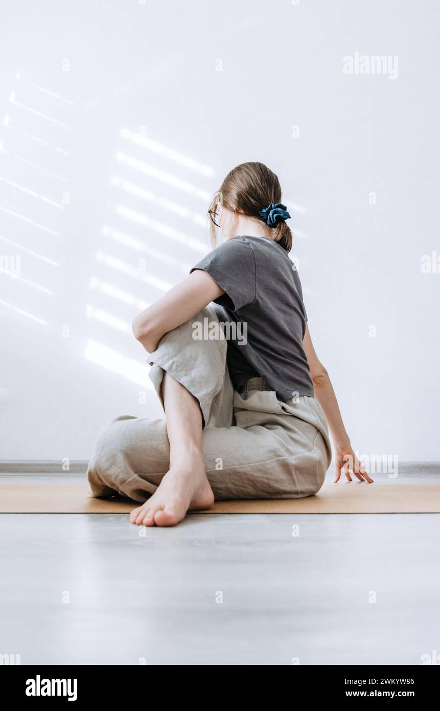Woman in casual clothes doing seated twist yoga pose on cork mat Stock ...