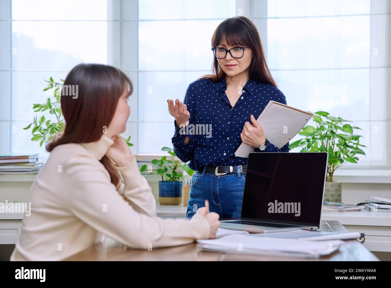Teenage student studying at desk with computer, trainer mentor helping ...