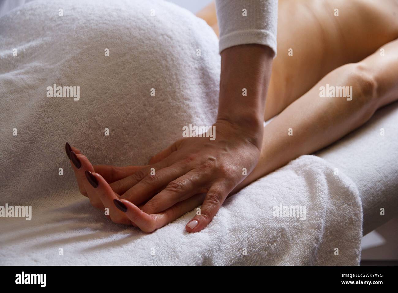 hands of a masseuse doing a hand massage to a girl with oil in a spa ...