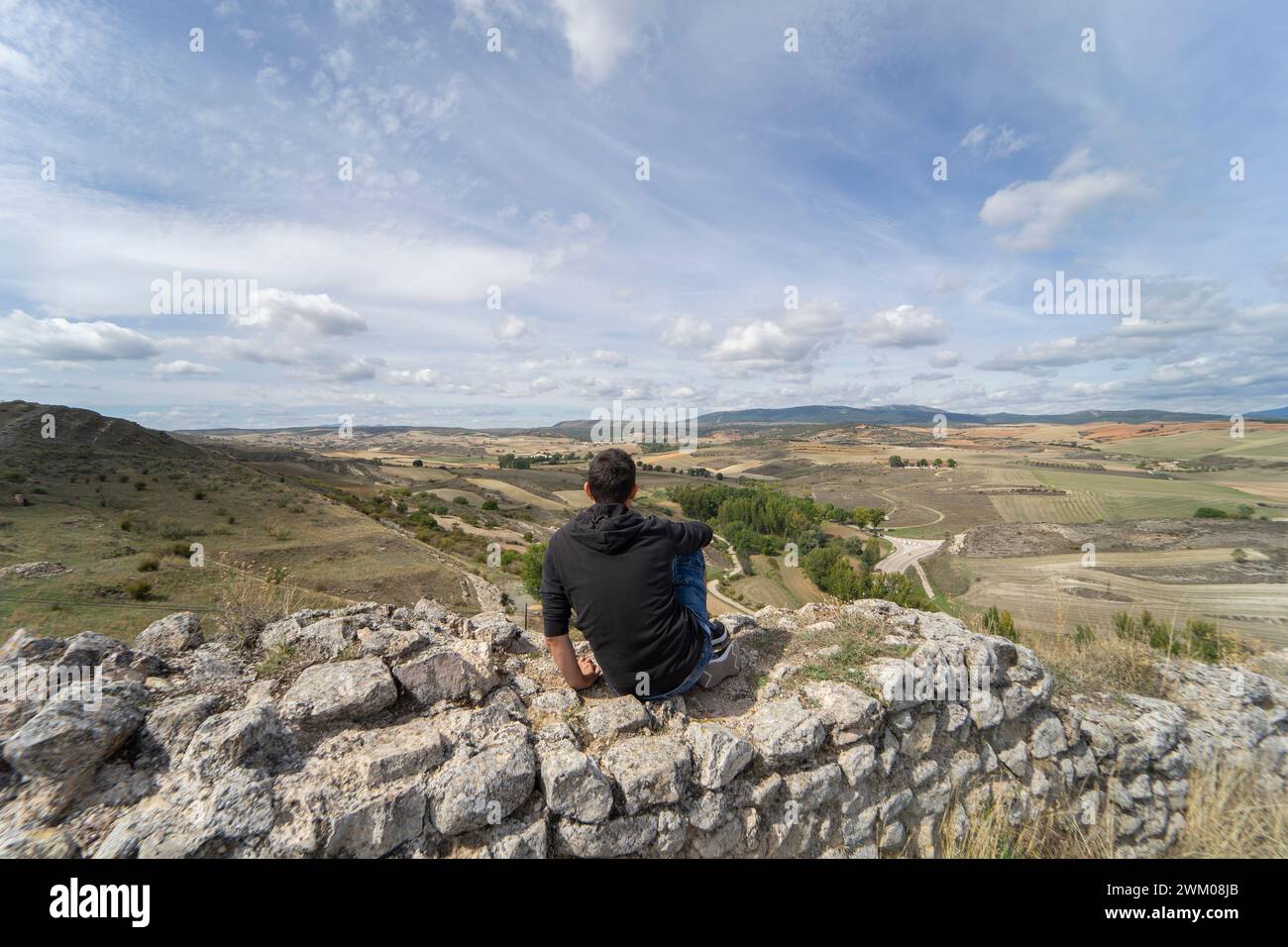 Thoughtful person in sportswear sitting on a rock on top of a lookout ...