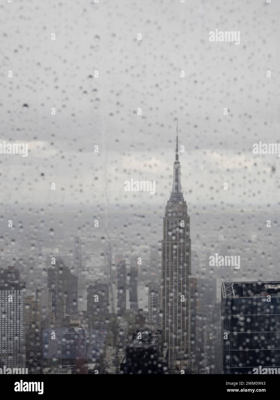 The Empire State Building in the rain, seen through a window with ...