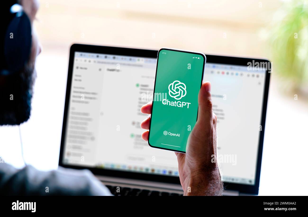 Man using ChatGPT in the mobile phone and the laptop. This app is a chatbot based on Artificial ...