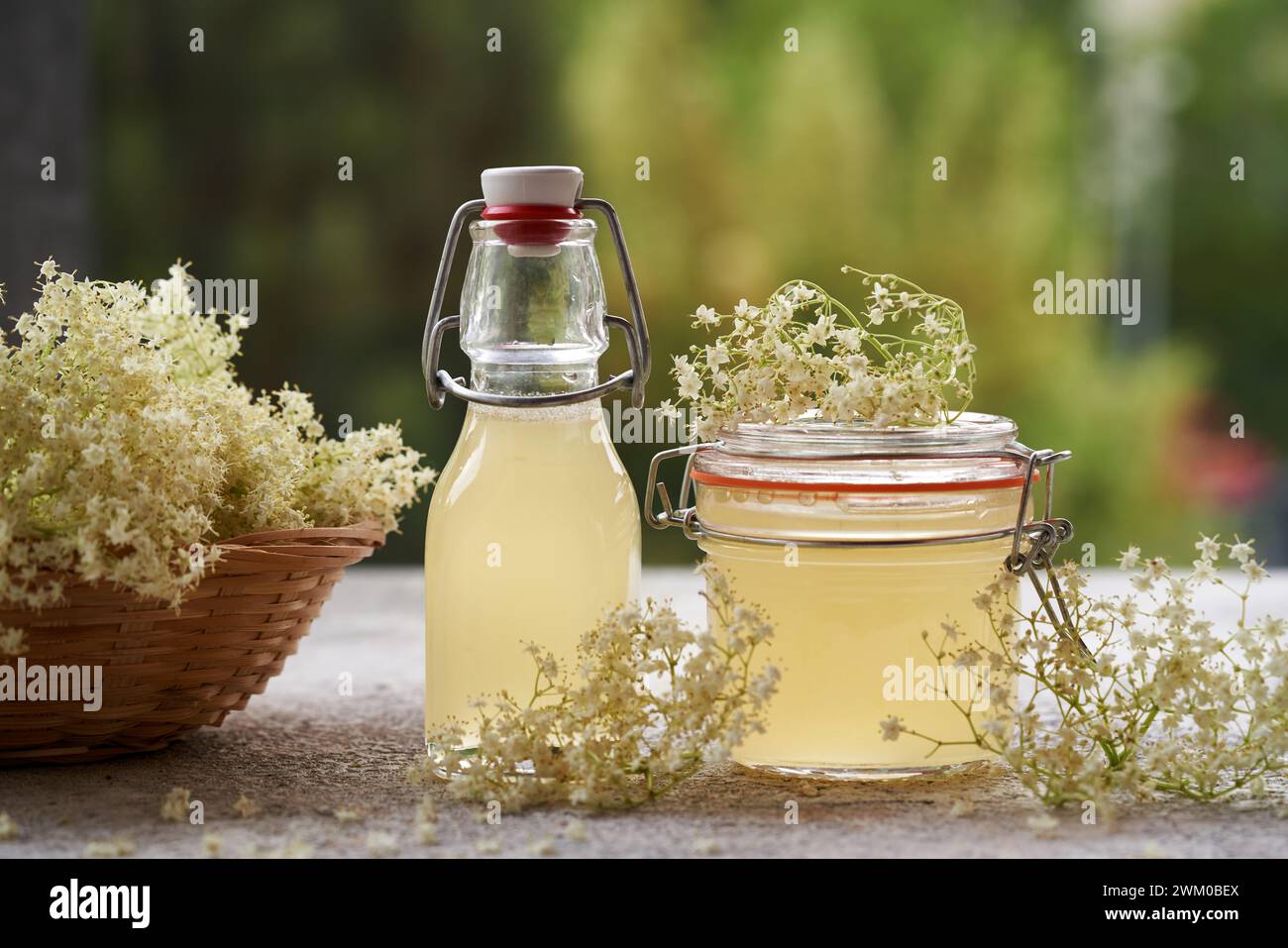 A bottle and a jar of elderberry flower syrup on a table outdoors Stock ...