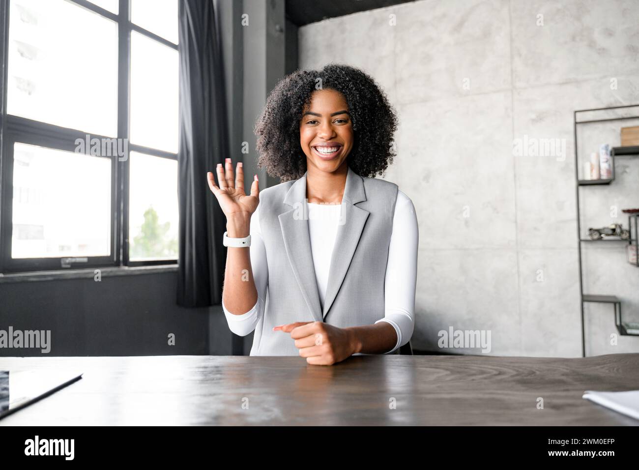 With a radiant smile and friendly wave, African-American woman greets ...