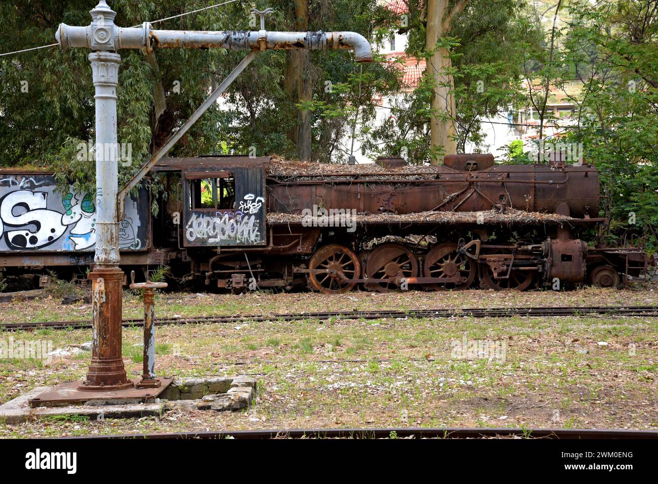 Rusty water crane and abandoned steam locos in the disused station yard ...