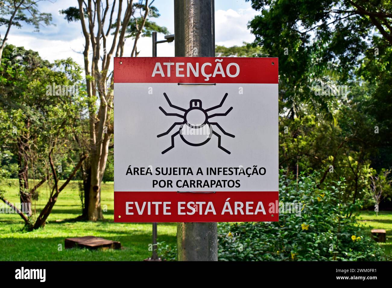 Warning sign in portuguese informing "Attention, area subject to tick ...