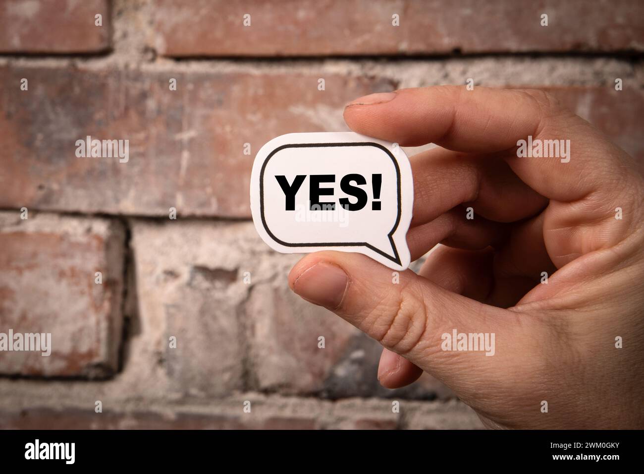 Yes Concept. Speech bubble with text in hand on brick background Stock ...