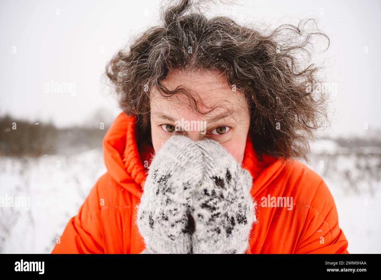 Mature woman covering face with hands in mittens Stock Photo - Alamy
