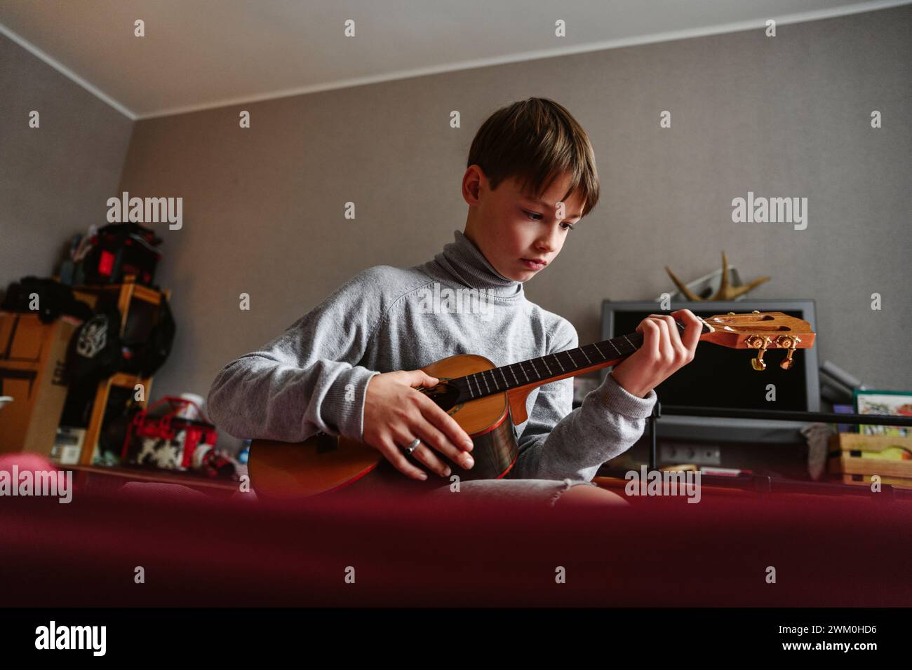 Boy playing ukulele at home Stock Photo - Alamy