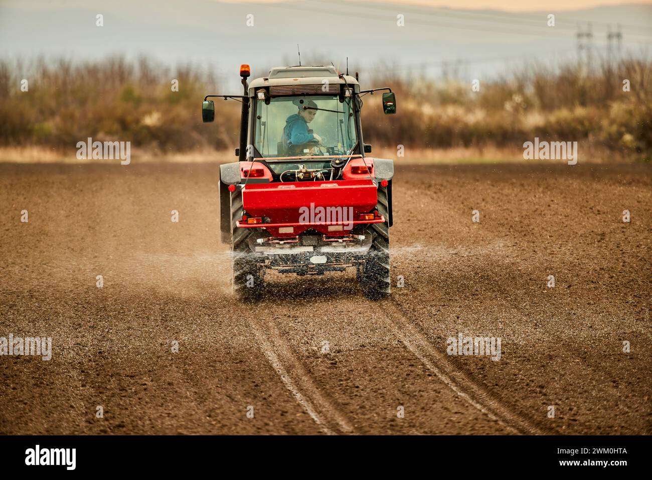 Farmer in tractor spraying fertilizer on field Stock Photo - Alamy
