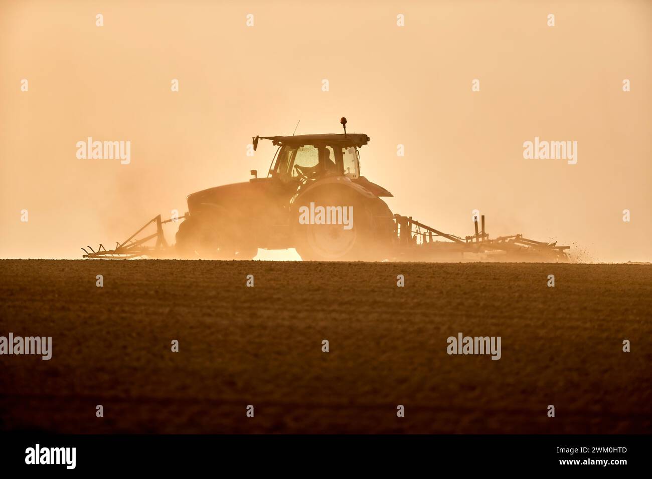 Farmer in tractor with plow preparing field Stock Photo - Alamy