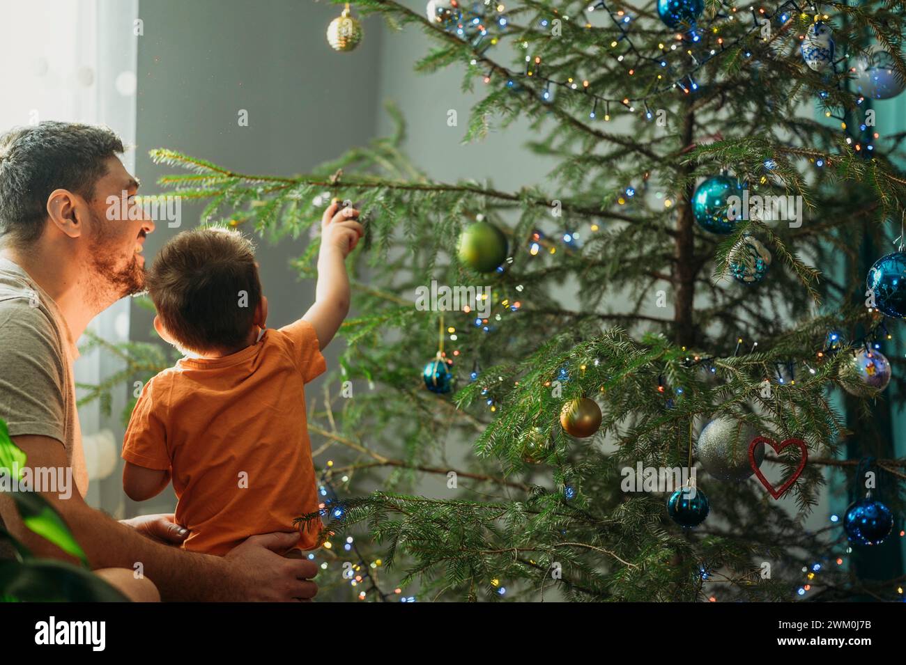 Boy decorating Christmas tree with father at home Stock Photo - Alamy
