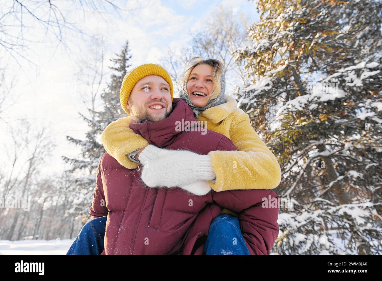 Happy man giving piggyback ride to young woman in winter forest Stock ...