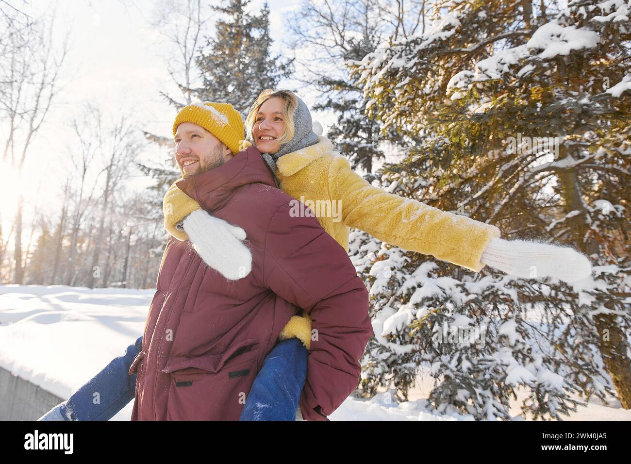 Happy man giving piggyback ride to woman in winter forest Stock Photo ...