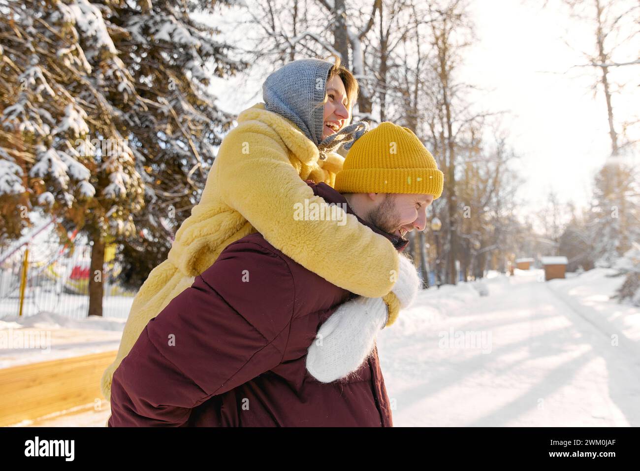 Smiling man giving piggyback ride to woman in winter Stock Photo - Alamy