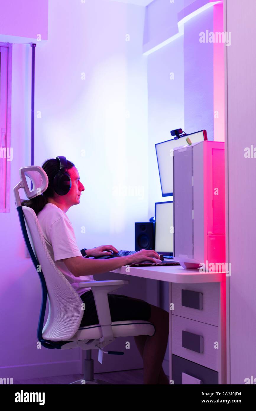 Professional gamer wearing headphones and playing game on computer ...