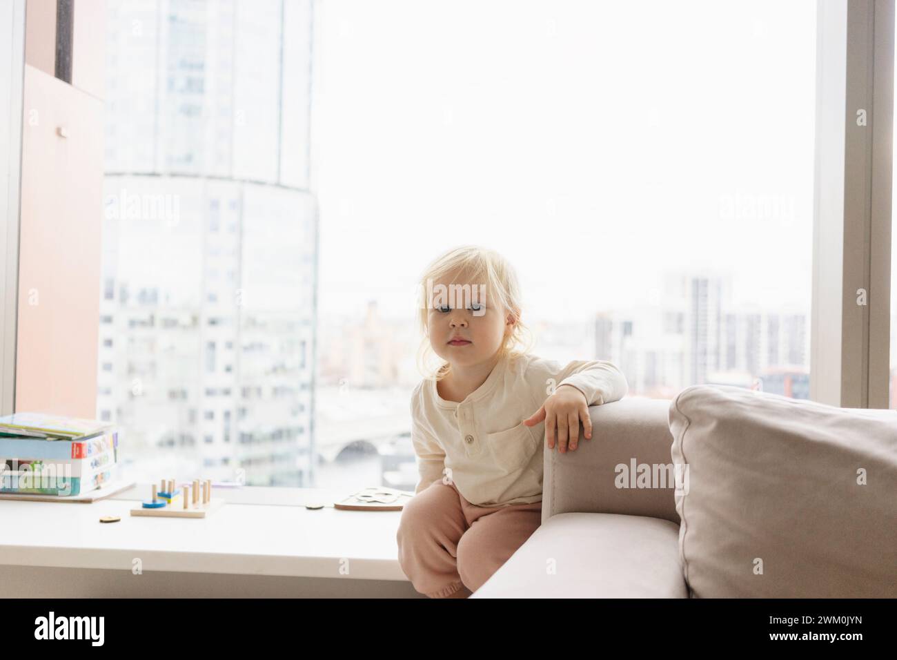 Little girl sitting on window sill at home Stock Photo - Alamy