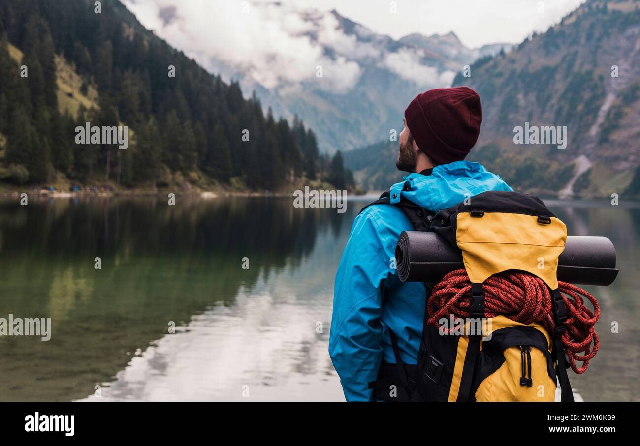 Man with backpack standing in front of lake Vilsalpsee and mountains at ...