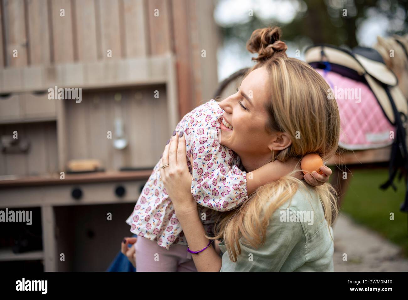 Happy mother hugging daughter near wooden horse Stock Photo - Alamy