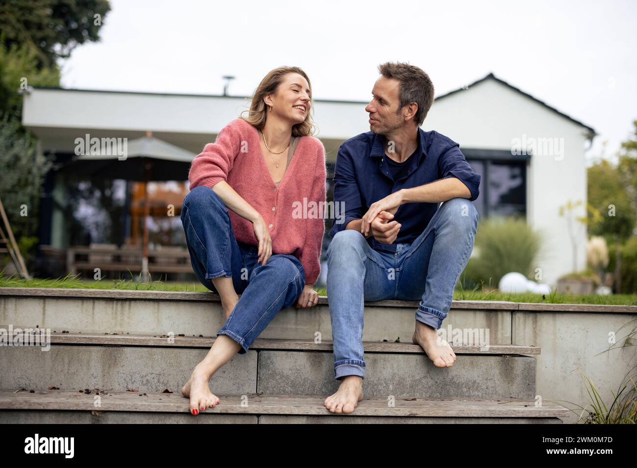 Happy couple sitting and talking to each other on steps in front of ...