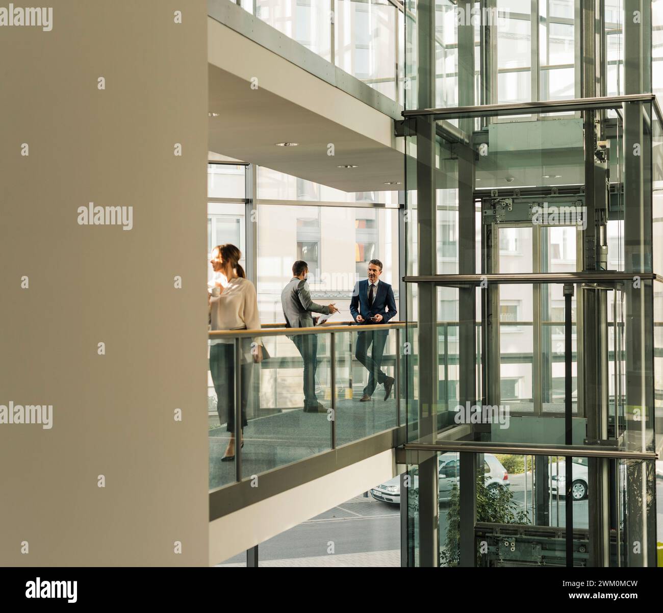 Coworkers talking on elevated walkway at office Stock Photo - Alamy