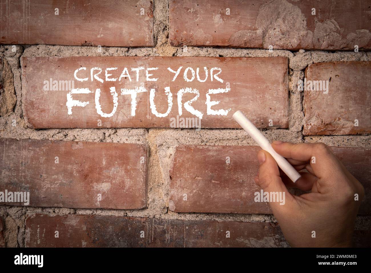 Create Your Future. Text written with white chalk on a red brick ...