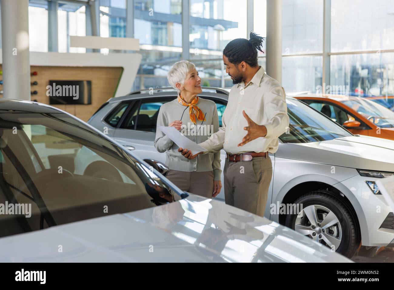 Salesperson discussing with smiling customer in car showroom Stock ...